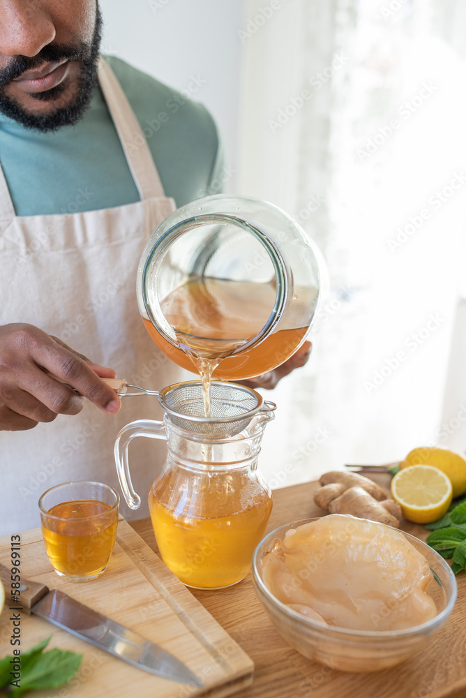 Making kombucha drink at home. Young black man making fermented drink ...