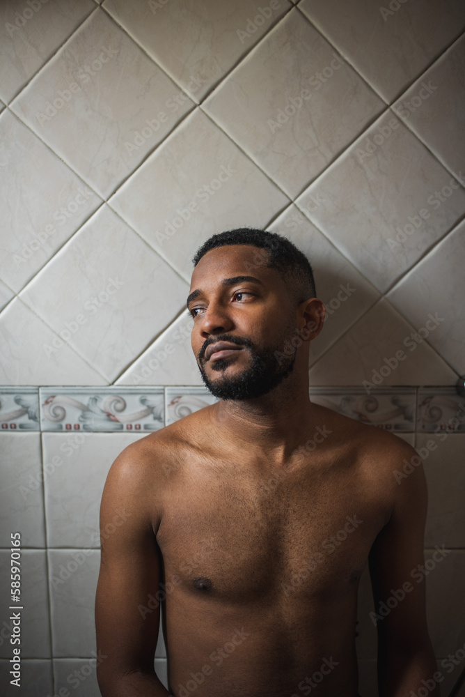 Young black shirtless sad man sitting alone in a bathroom. Sad ...