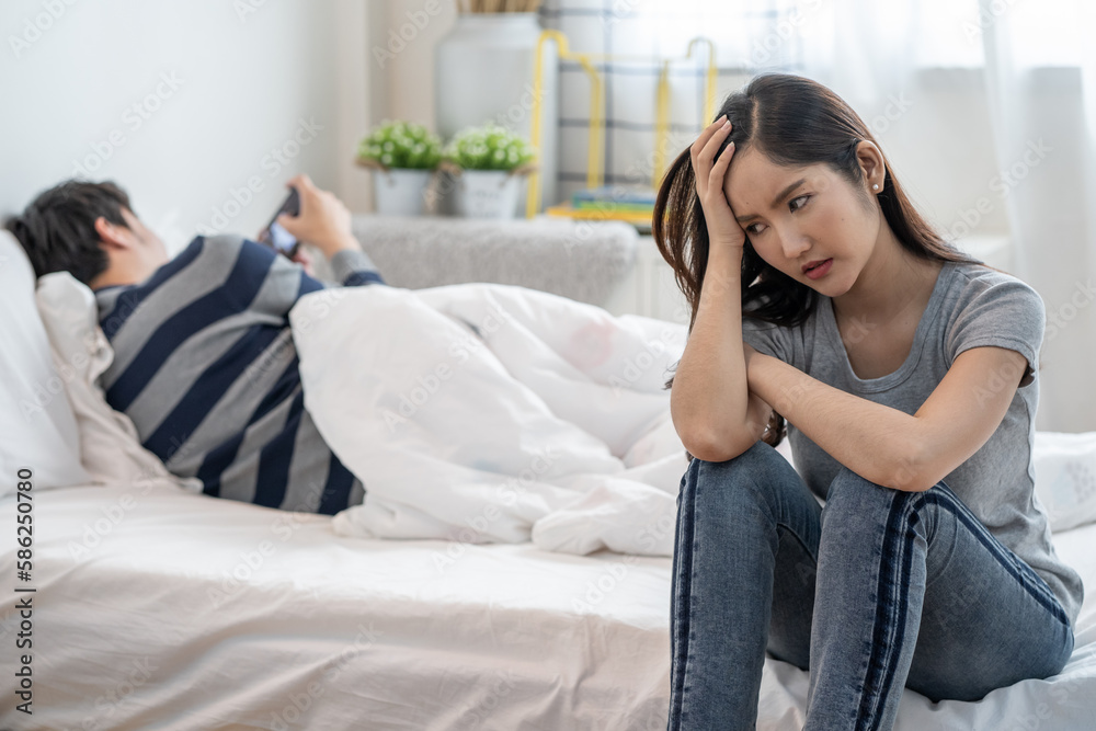 Asian young upset woman sitting on the bed, against her boyfriend, Wife ...