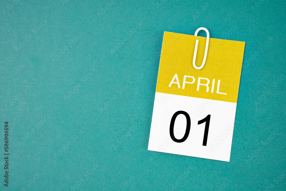 The April 1st calendar sheet with paper clip on dark green background ...