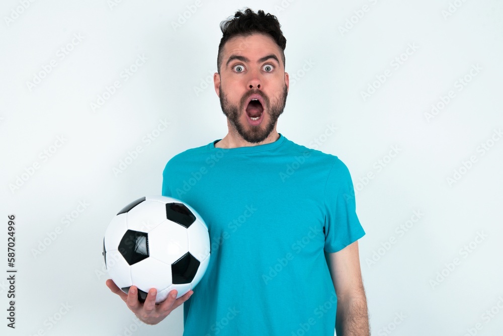 Oh my God. Surprised Young man holding a ball over white background ...
