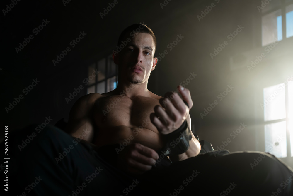 Shirtless bodybuilder man wrapping his hand with bandage inside the gym ...