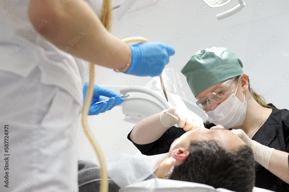 remove a tooth Male Dentist remove tooth of man patient using forceps ...