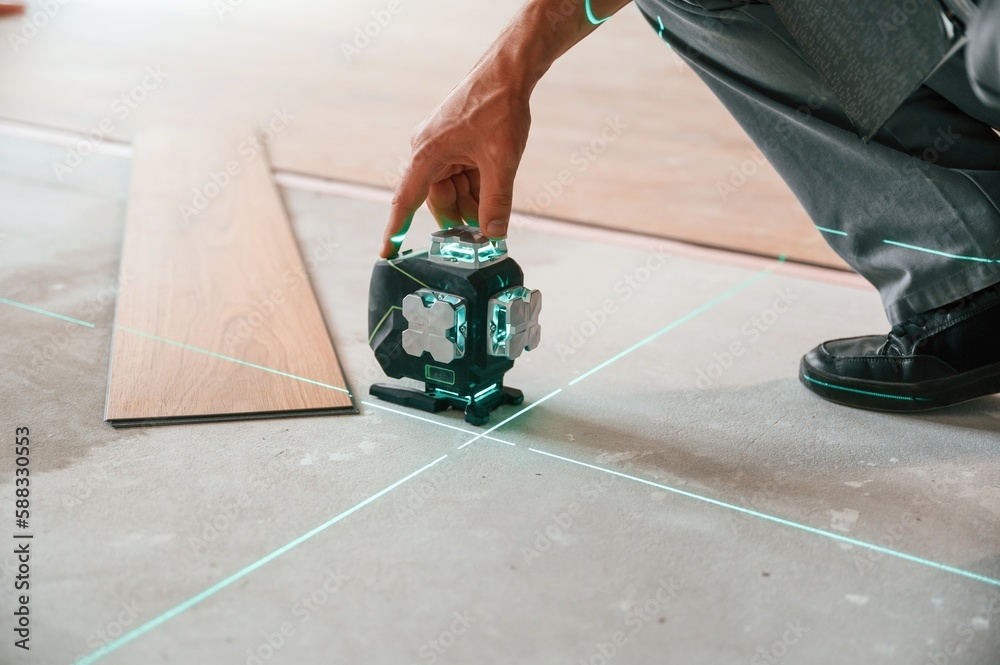 Using the device that shows straight lines by laser. Man is installing ...