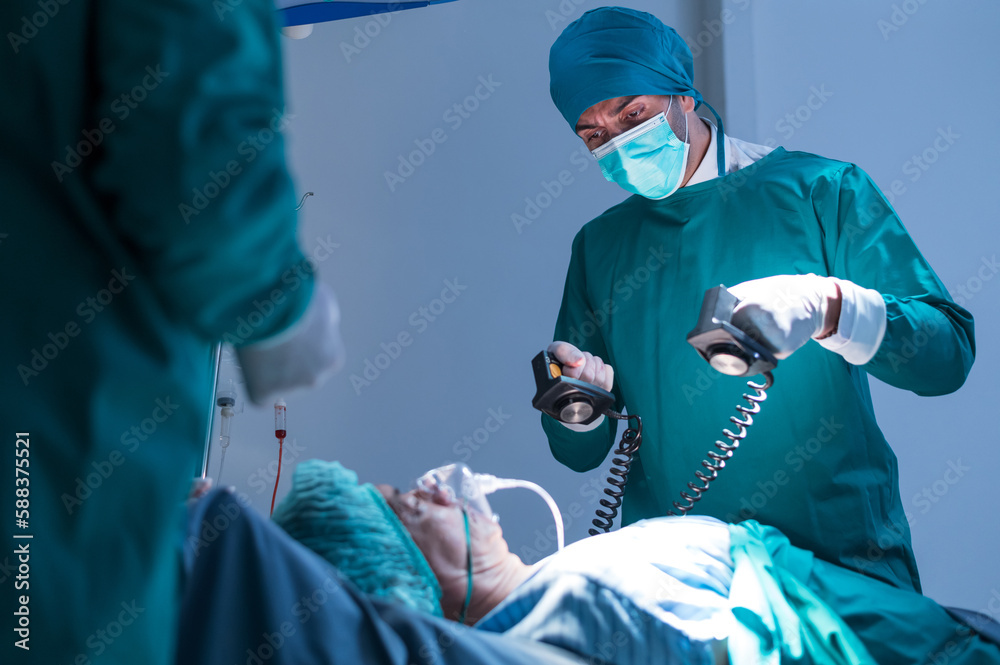 concentrated surgeon doctor using defibrillator to give electrical ...