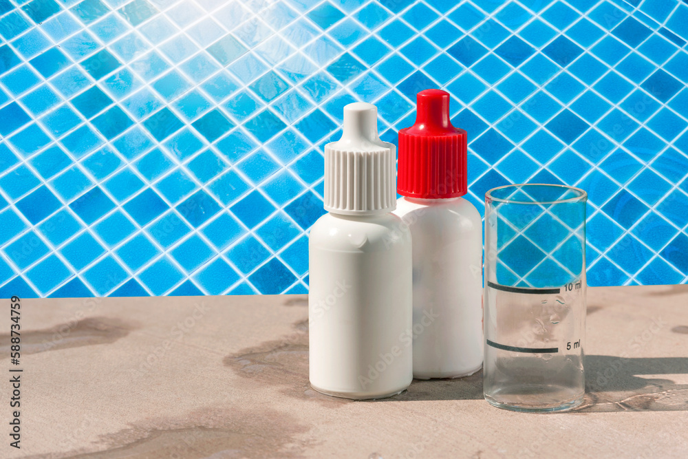 Plastic bottle of pH and Chlorine solution with glass beaker over ...