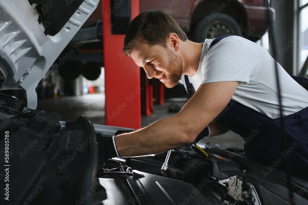 Handsome young male auto mechanic in special uniform clothes holding a ...