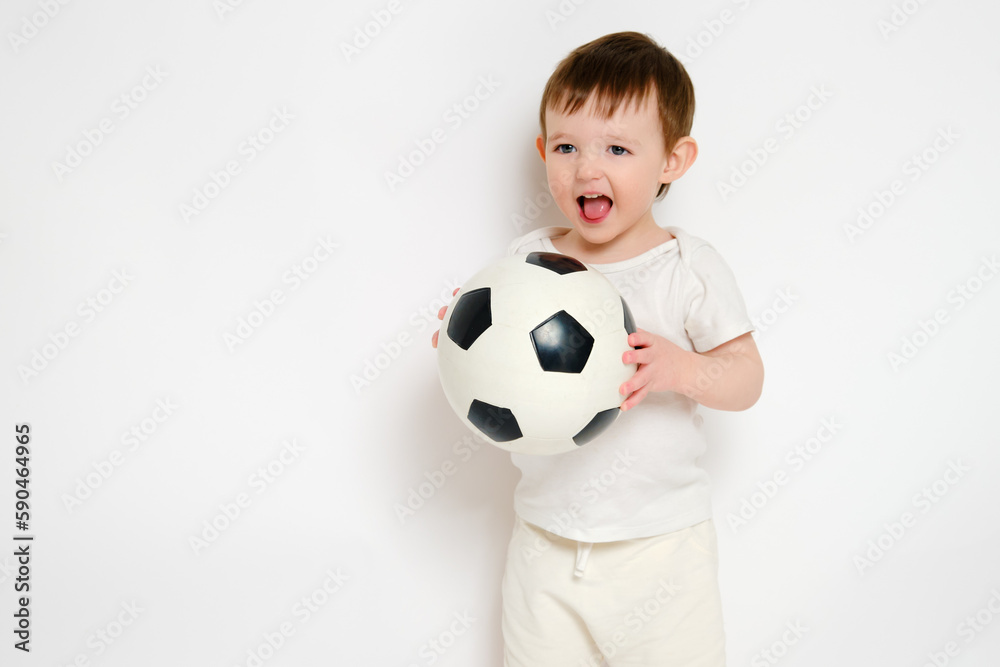 Happy baby holding a soccer ball on a studio white background. Smiling ...