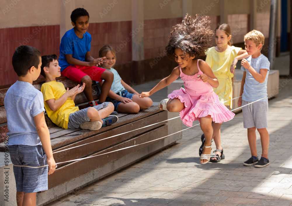 Happy little girl jumping game by rubber band with friends on the ...