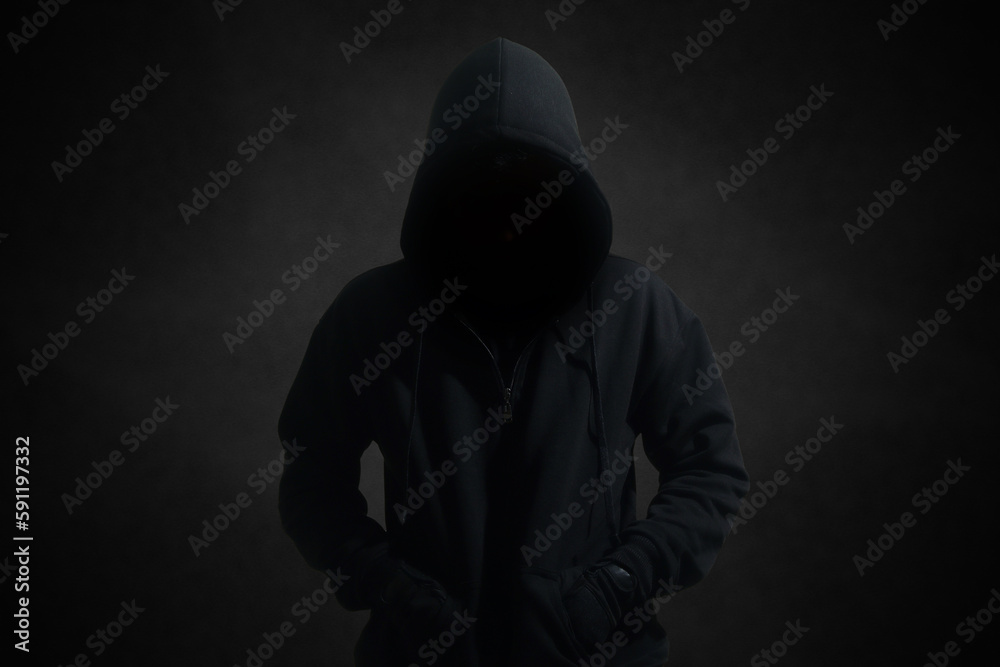 Mysterious man wearing black hoodie standing against dark background ...