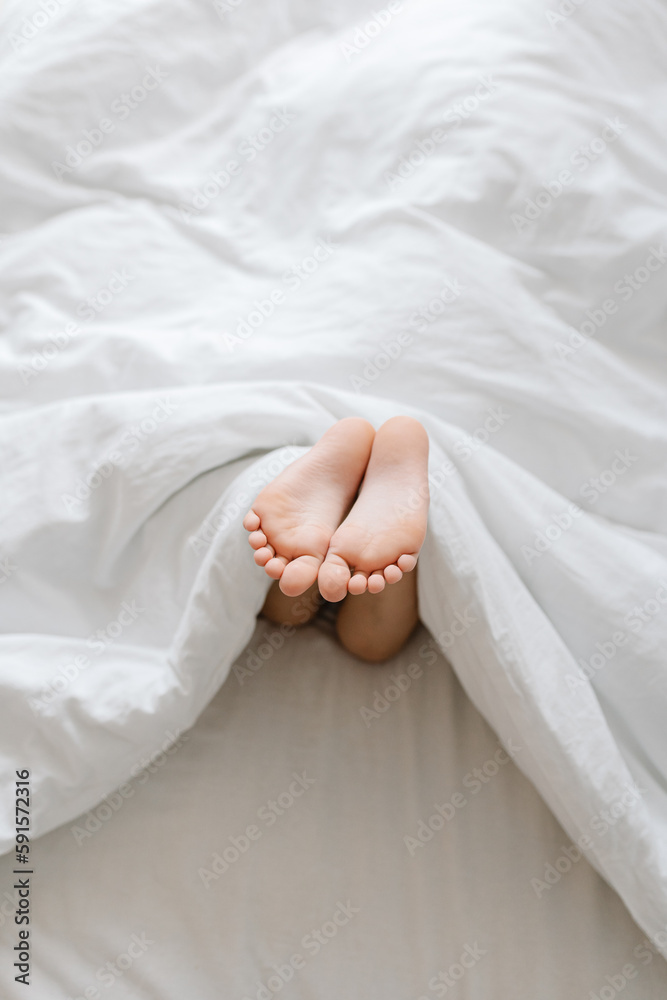 Feet of little girl on bed under white blanket, sleep at morning. Stock ...