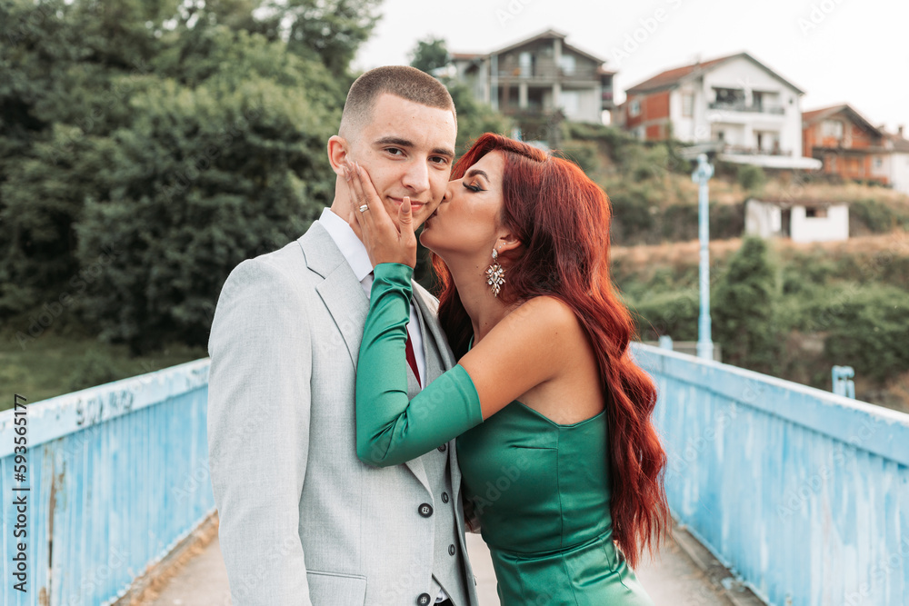Foto Teenage couple dressed up for the prom. Girl kissing her prom gate ...