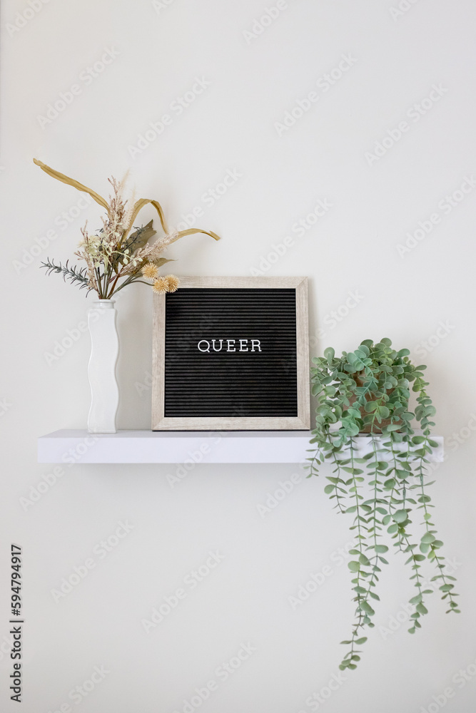 queer lettering on a black and tan letter board sitting on a floating ...