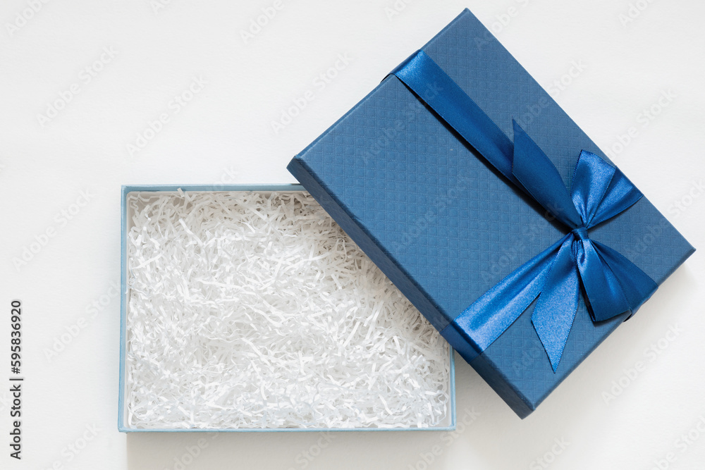 Open gift box with shredded paper on a white background. Blue cardboard ...
