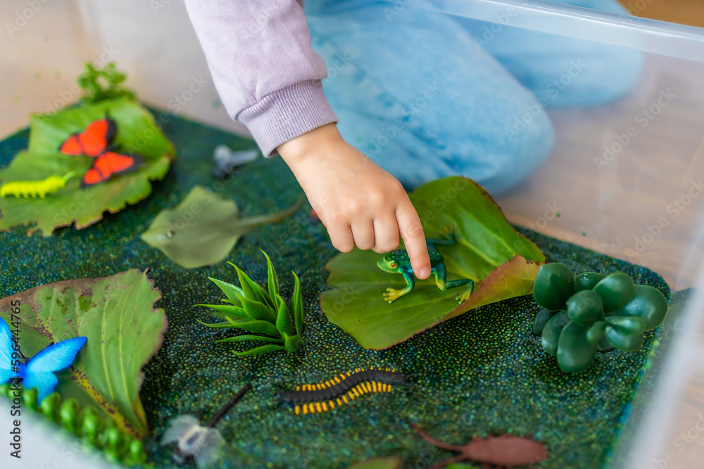 Little girl playing in handmade swamp of green-dyed chia seeds with ...