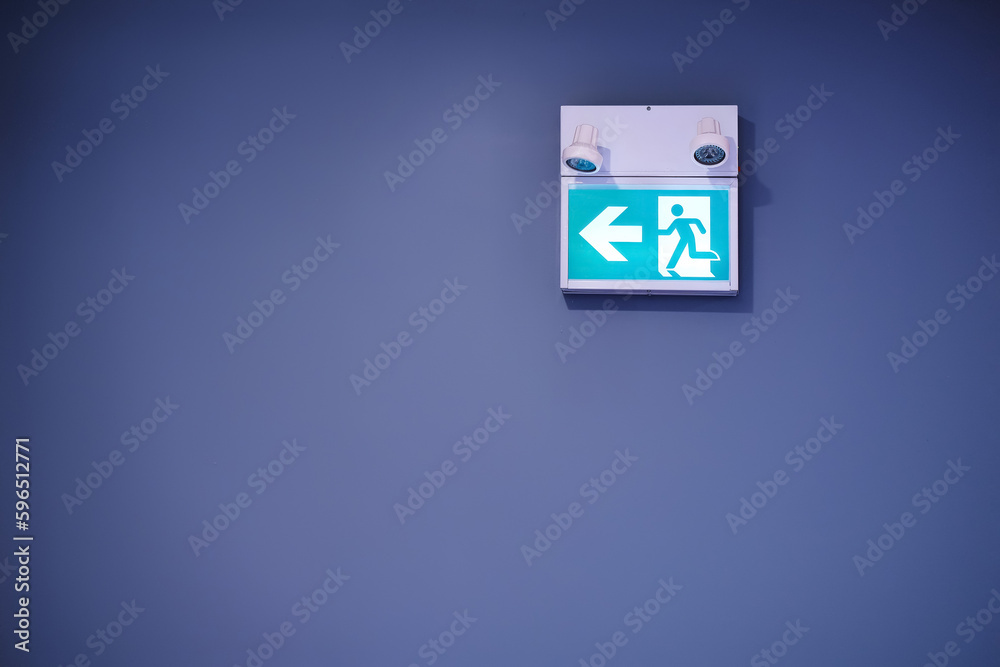 Green fire exit sign on textured wall with emergency lights. Fire ...