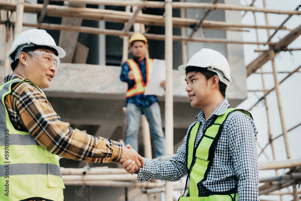 construction worker wearing a protective helmet and vest is holding his ...
