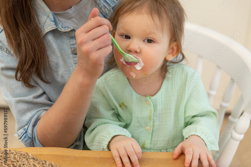 Happy family at home. Mother feeding her baby girl from spoon in ...