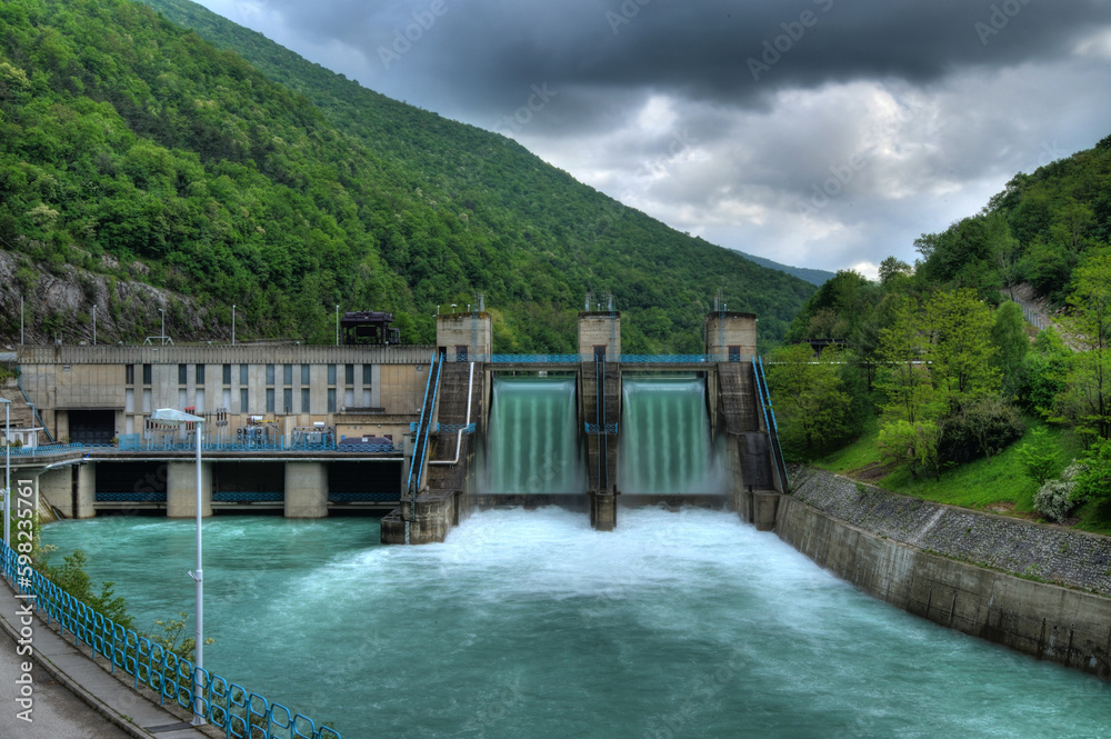 hydroelectric power plant dam on a river with water overflowing the dam ...