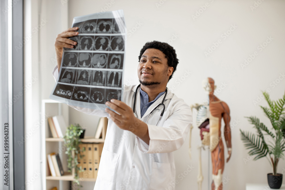 Mindful multicultural person in lab coat holding CT image of brain scan ...