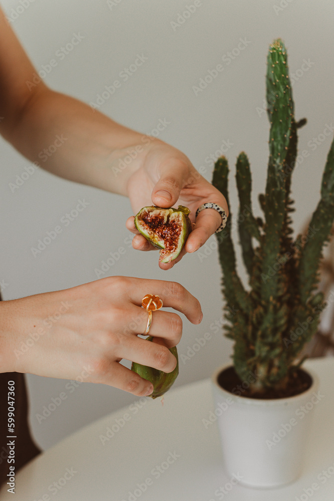 female hands with golden rings on the fingers are holding a fig cut in ...