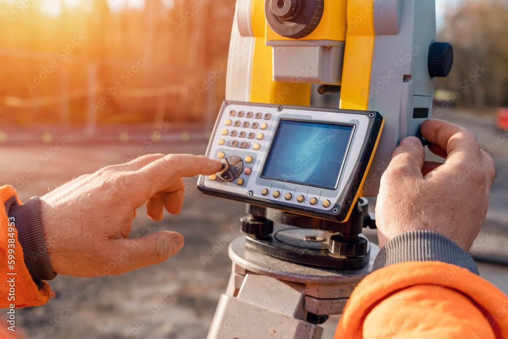 Site engineer operating his instrument during roadworks. Builder using ...
