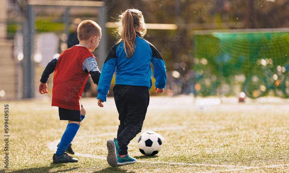 Little boy and girl running and kicking soccer ball. Football lesson ...