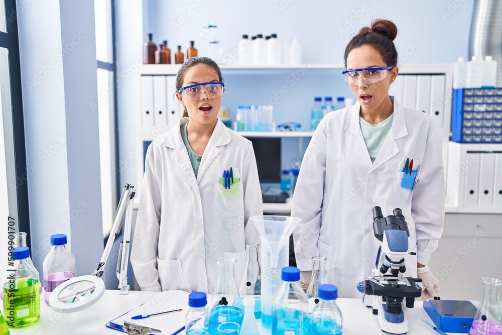 Young mother and daughter at scientist laboratory scared and amazed ...