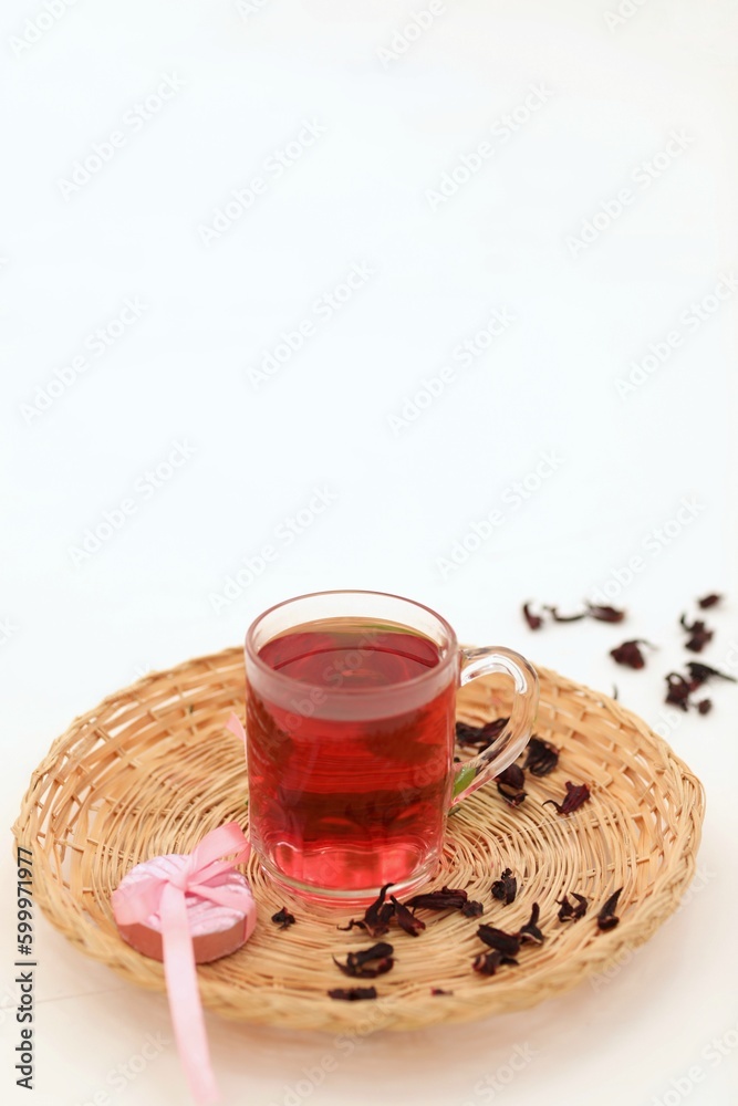 Karkade tea in a transparent cup, dry leaves of the karkade flower, a ...
