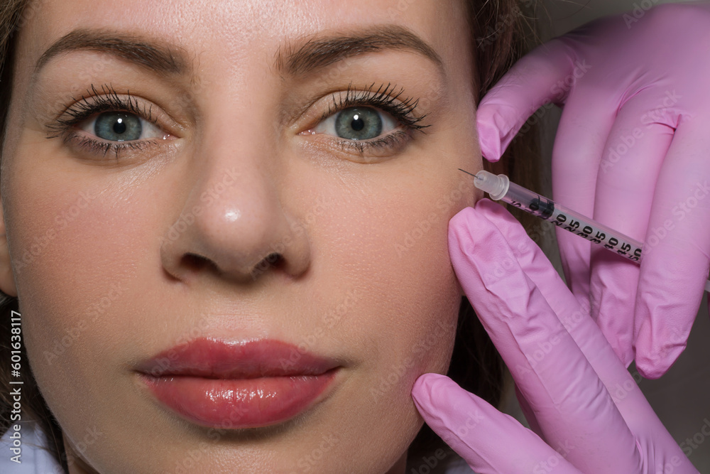 Beautiful young woman is getting botox injection at clinic. She is ...