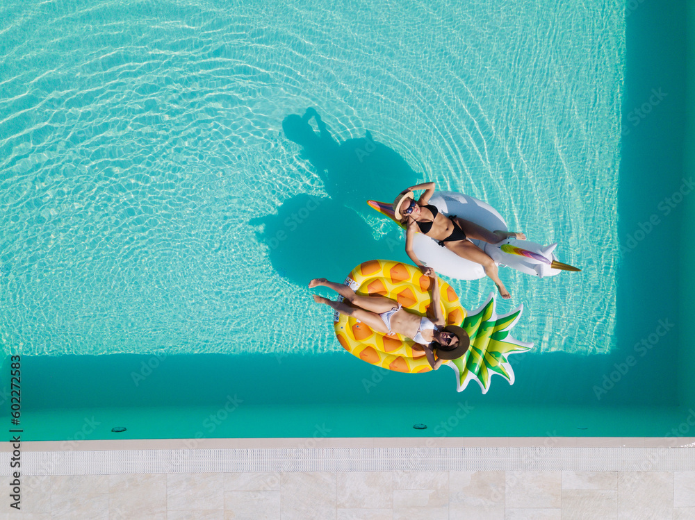 Top view of female friends wearing bikini lying on an inflatable toy in ...