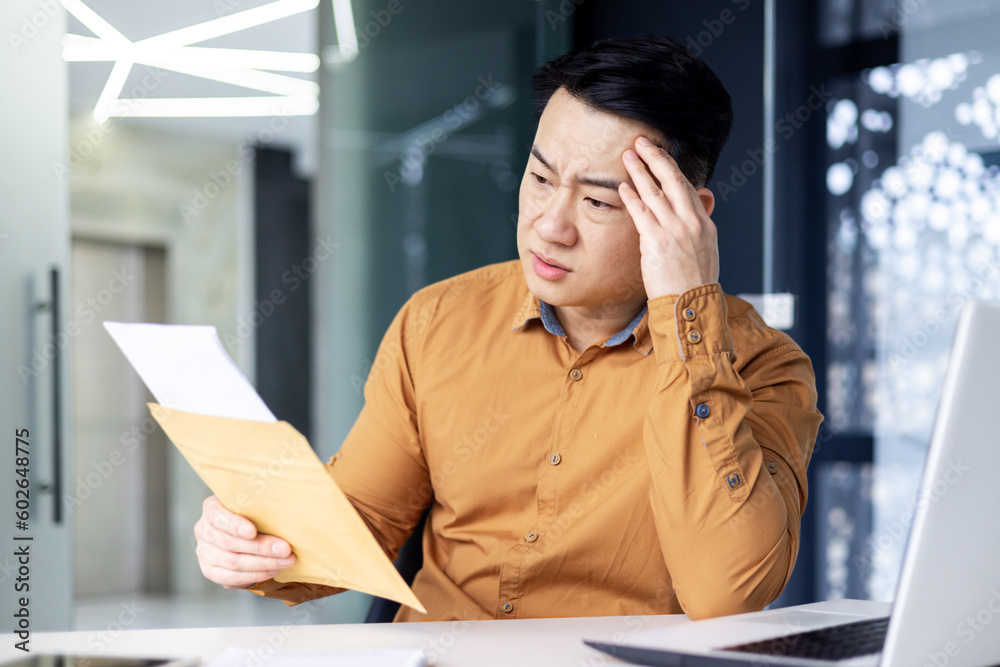 Serious and upset asian businessman reading letter with bad news ...