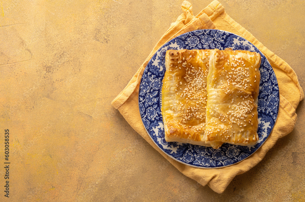 Puff pastry dough. Folded baked puff pastry pie in a plate, warm orange ...