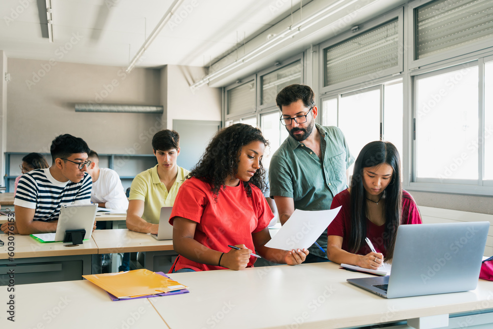 Young teacher explaining exercise to teenager girl students at High ...