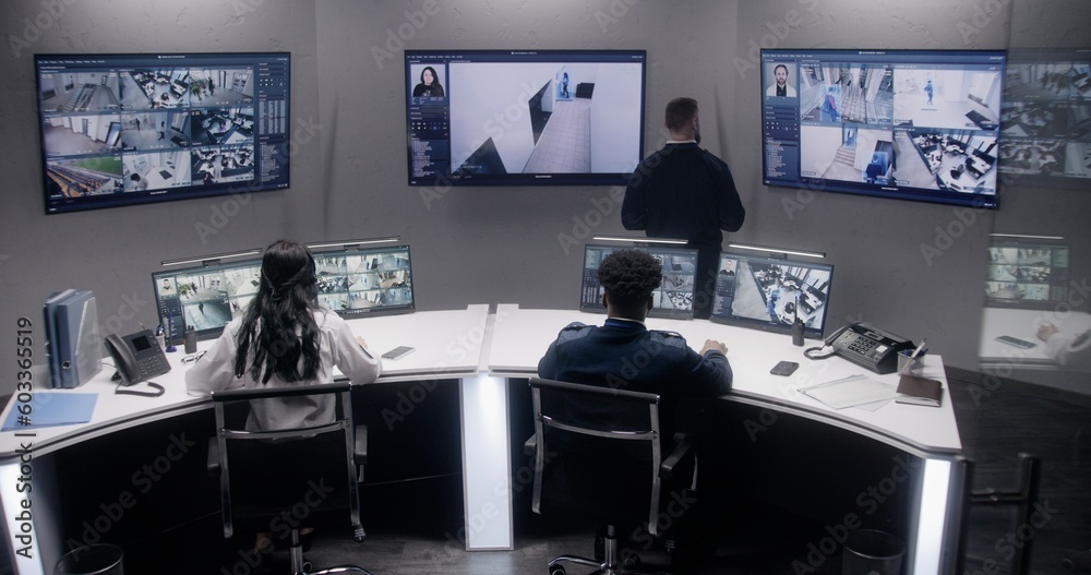 Multi ethnic security officers monitor CCTV cameras with AI face ...