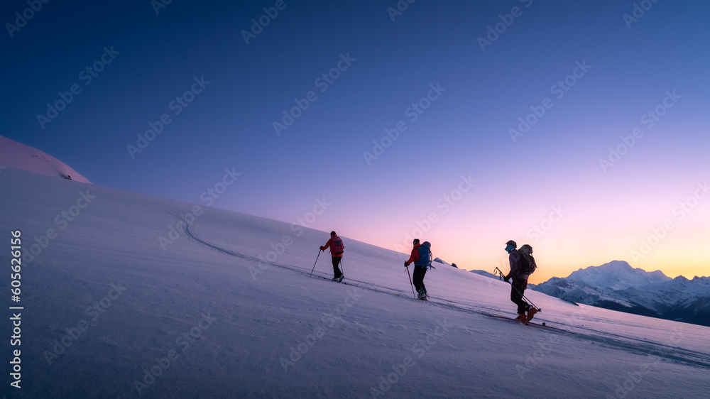 Skiers touring in winter, full of snow, at sunrise under a beautfiul ...