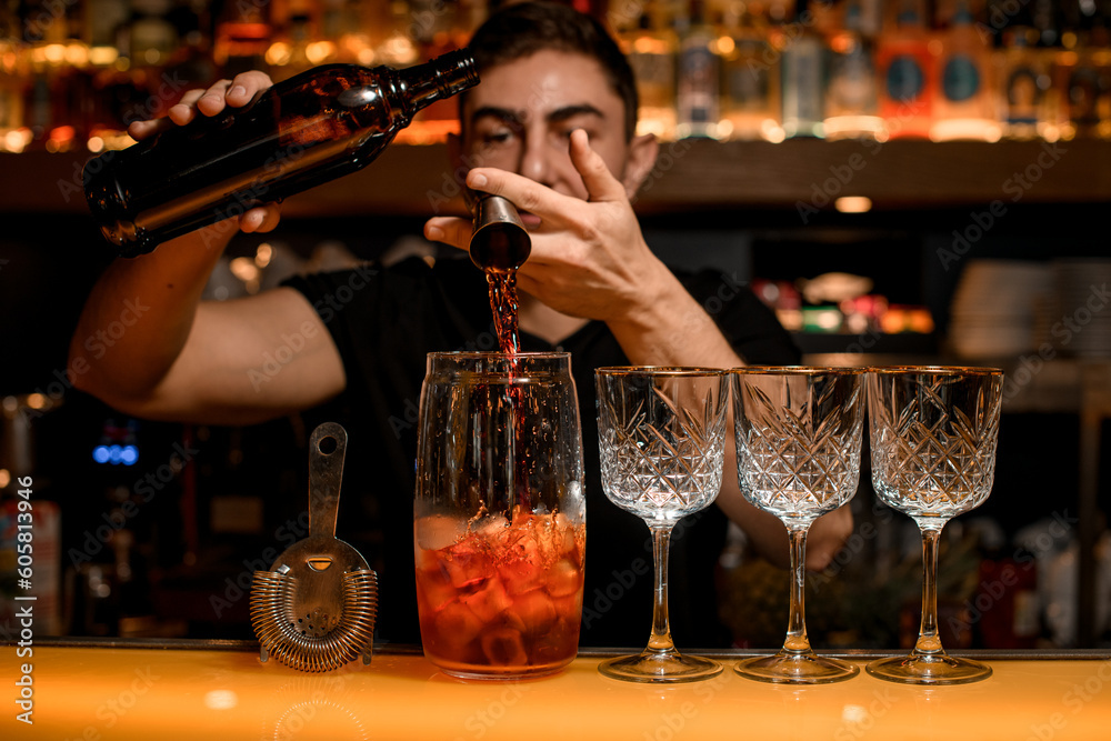 Tools for making cocktails and drinks stands on the bar counter and bartender adds an ingredient ...