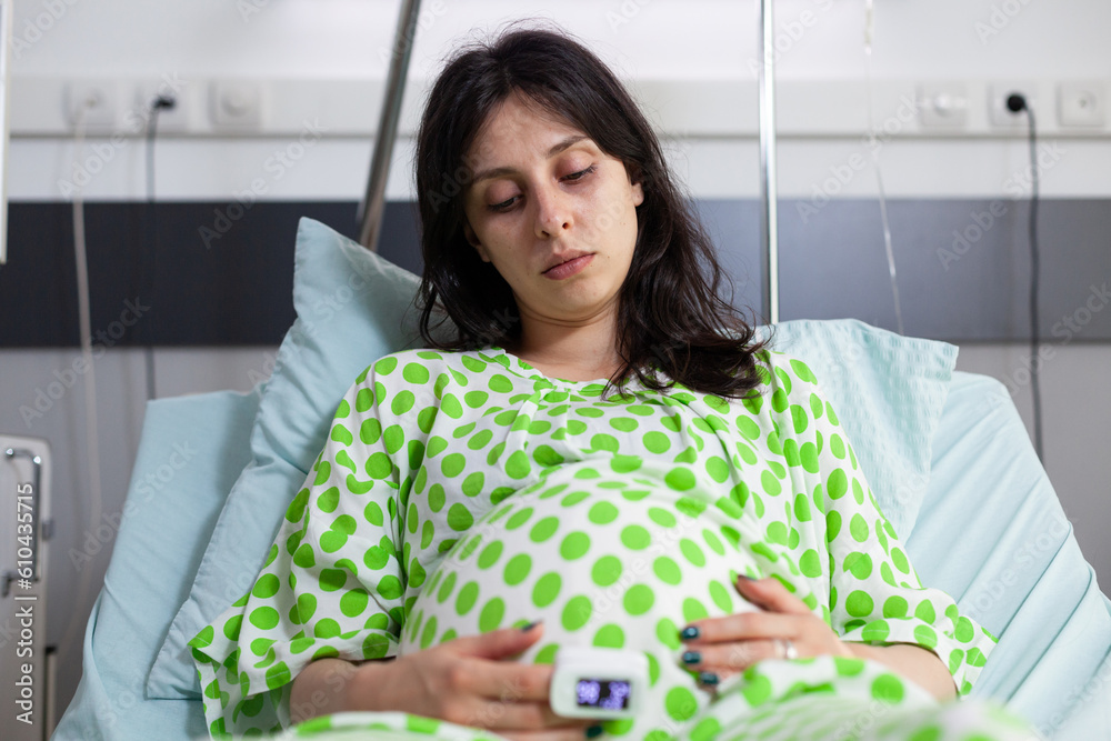 Pregnant woman holding hand on belly, lying in bed preparing for ...