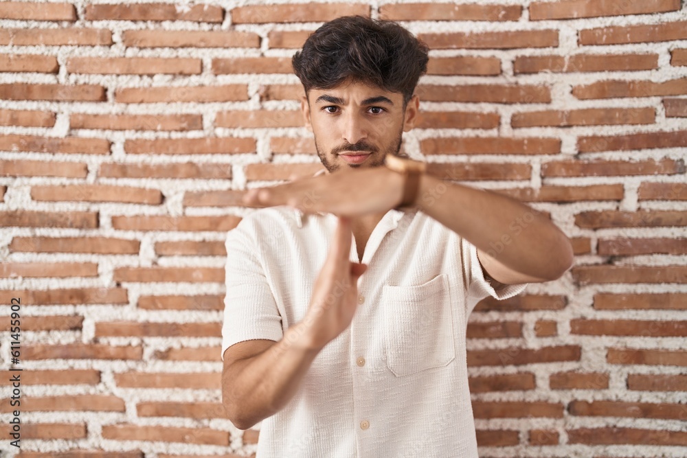 Arab man with beard standing over bricks wall background doing time out ...