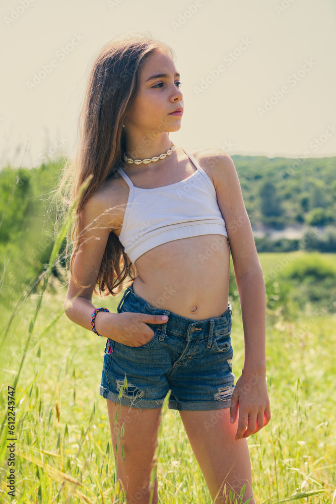 A pretty 9-year-old girl is standing in a field in a rural area on a hot summer day Stock Photo ...