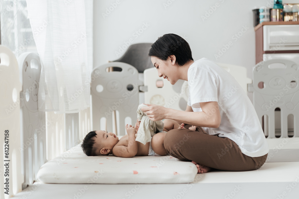 Cute Asian baby wearing clothes by his mother after changing him diaper ...