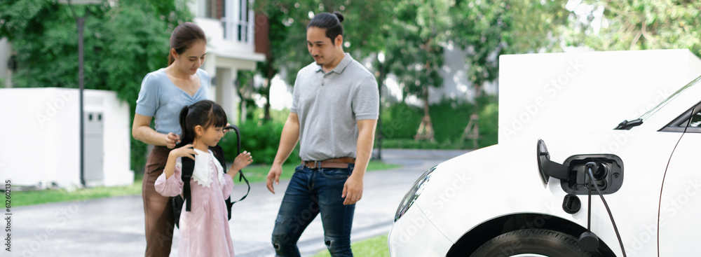 Progressive young happy family with electric vehicle and home backyard ...