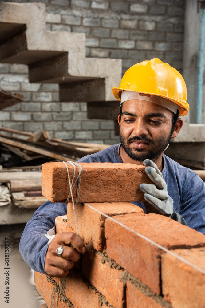 Happy Indian male construction worker constructing brick wall - hard ...