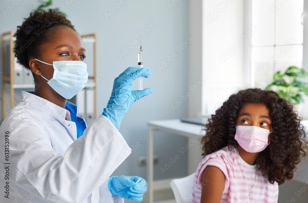 Vaccination. African American female doctor prepares syringe with ...