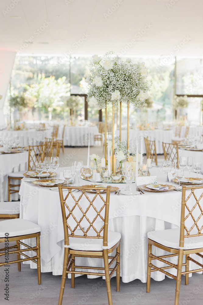 Served wedding tables with golden plates, decorative fresh white roses ...
