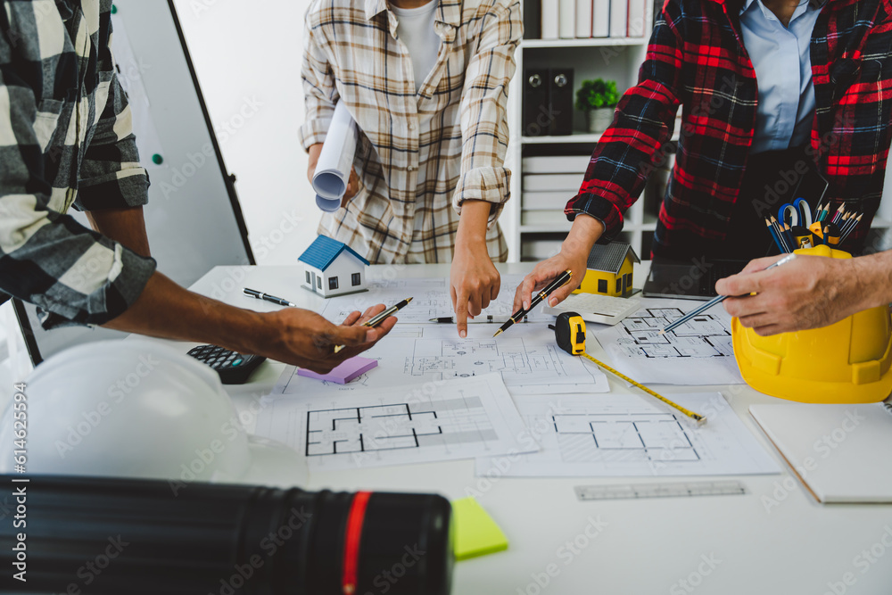 Engineers work as a team with blueprints for architectural plans ...
