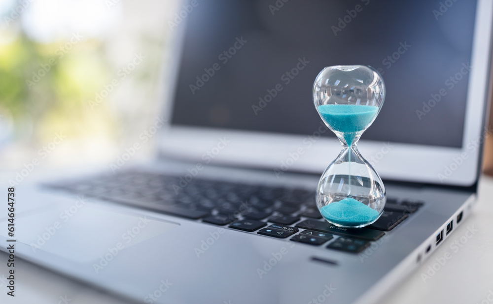 Hourglass on laptop computer concept for time management background ...