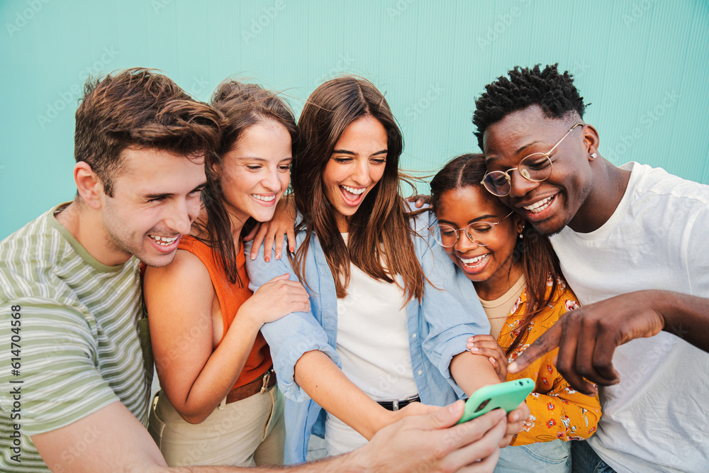 Multiracial group of young friends enjoying and smiling using their ...