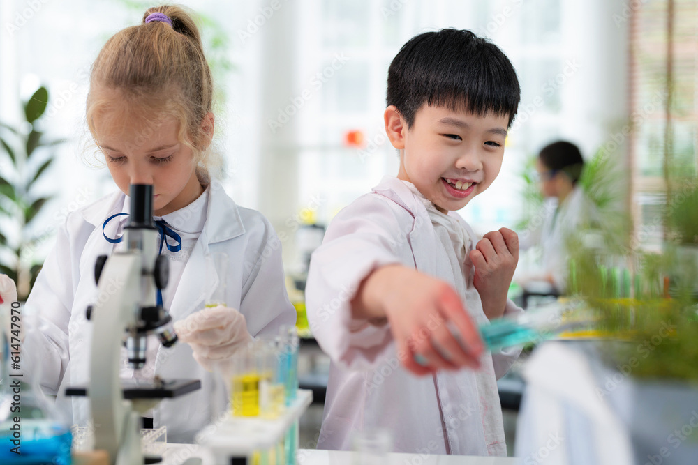 Asia cute boy wearing lab coat pouring blue solution from test tube ...