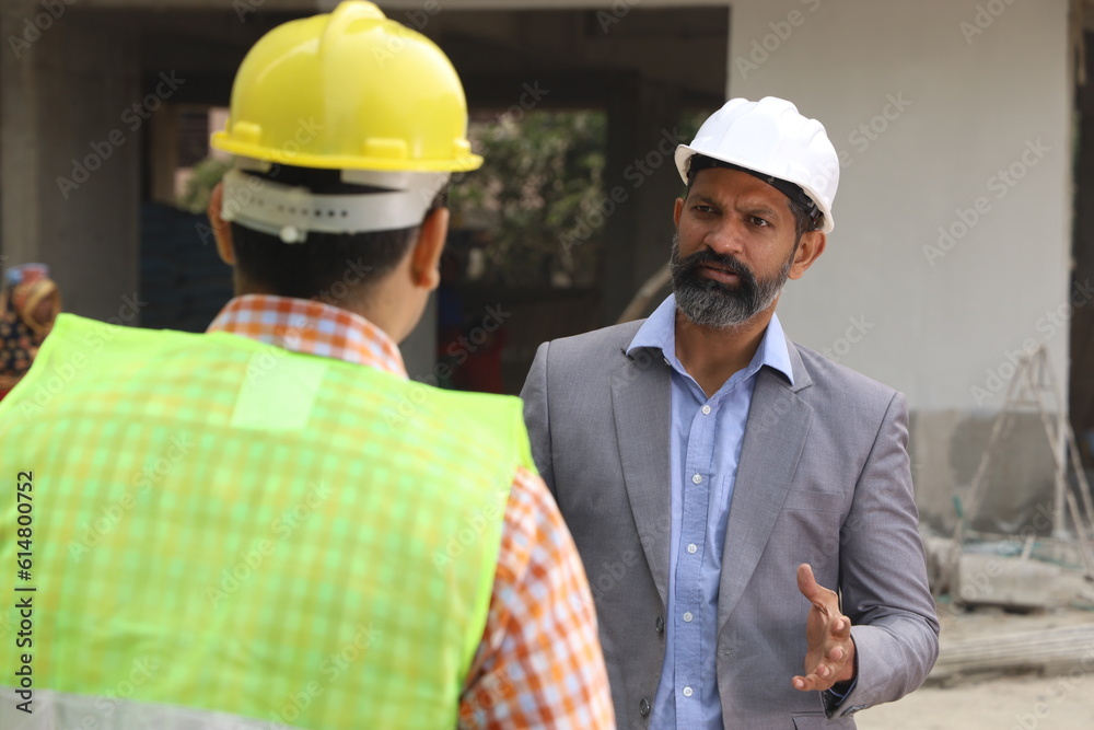 Hardworking Indian Site engineer and manager analyzing the blueprint ...